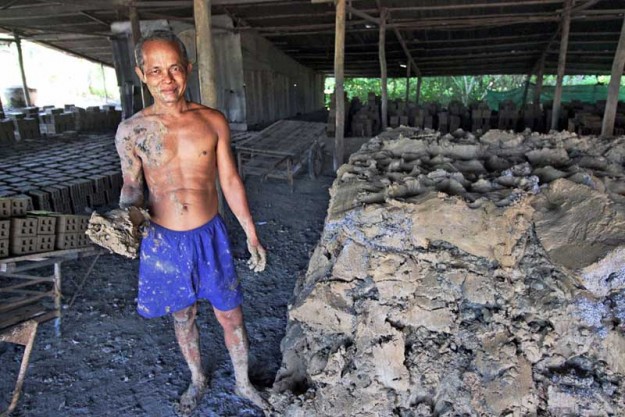 PHOTO: Worker prepares clay used for production of bricks near ...